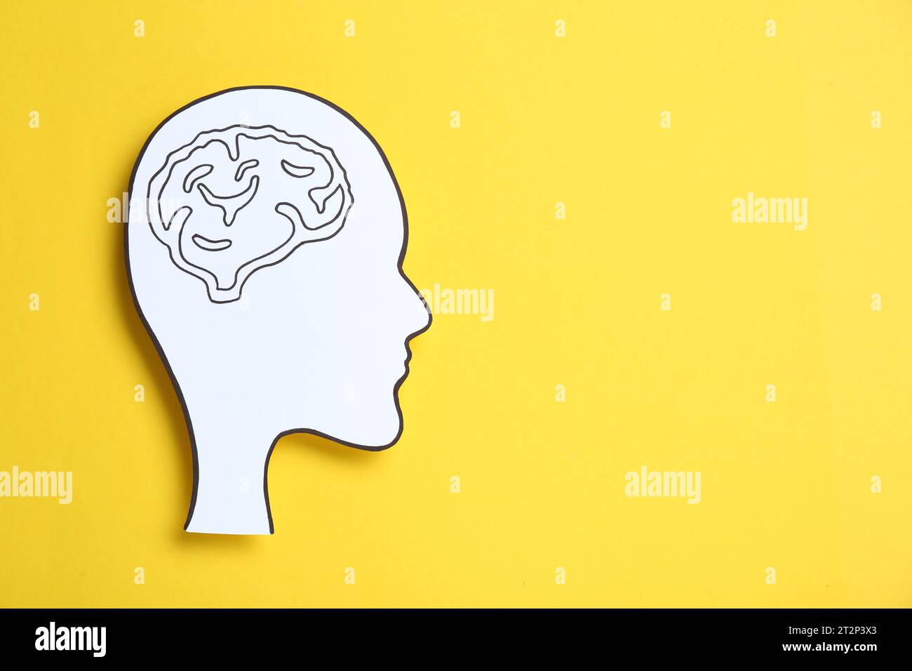 Paper human head cutout with drawing of brain on yellow background, top ...