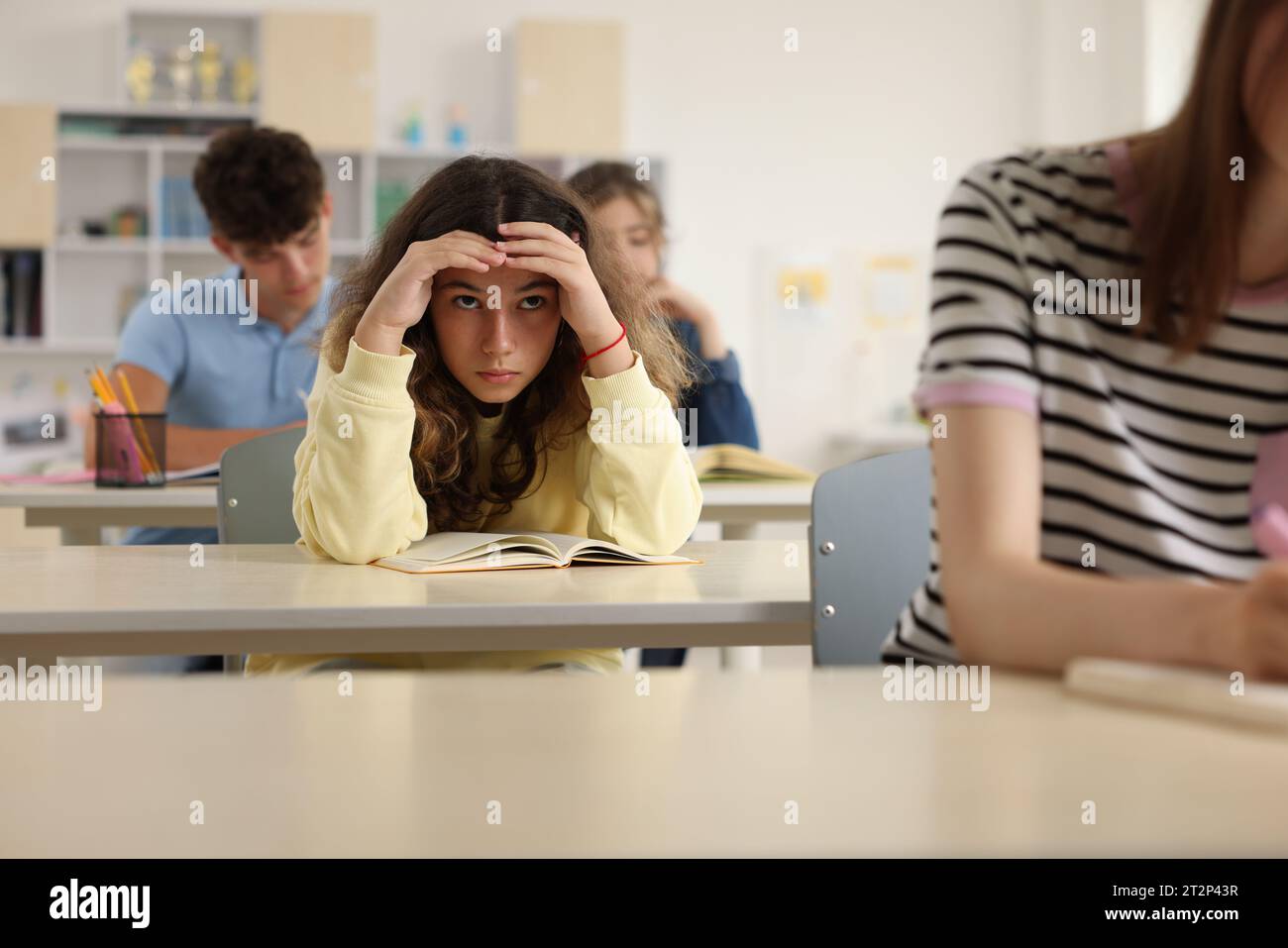 Teen problems. Lonely girl sitting separately from other students in ...
