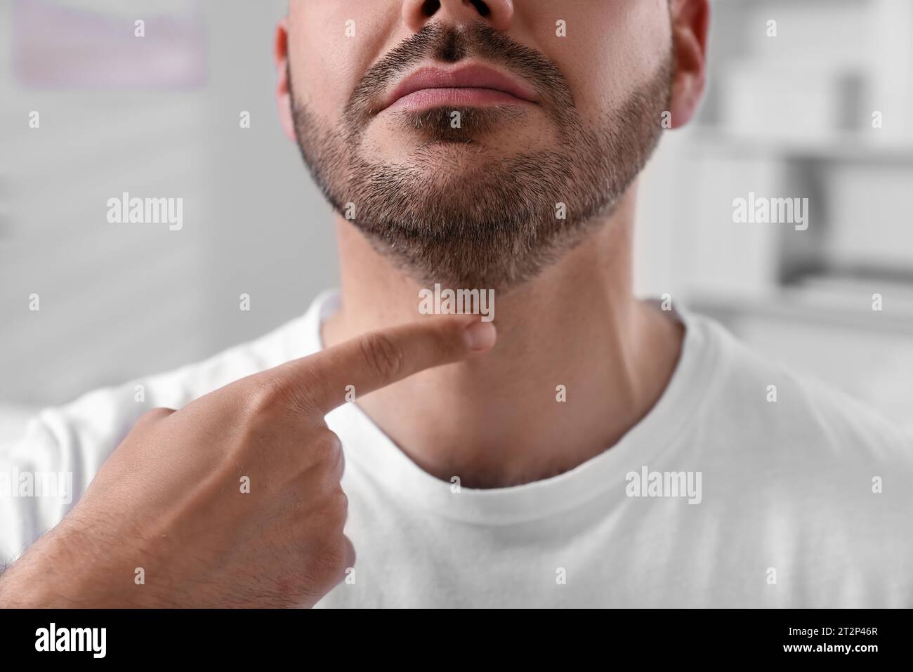 Endocrine system. Man doing thyroid self examination indoors, closeup ...