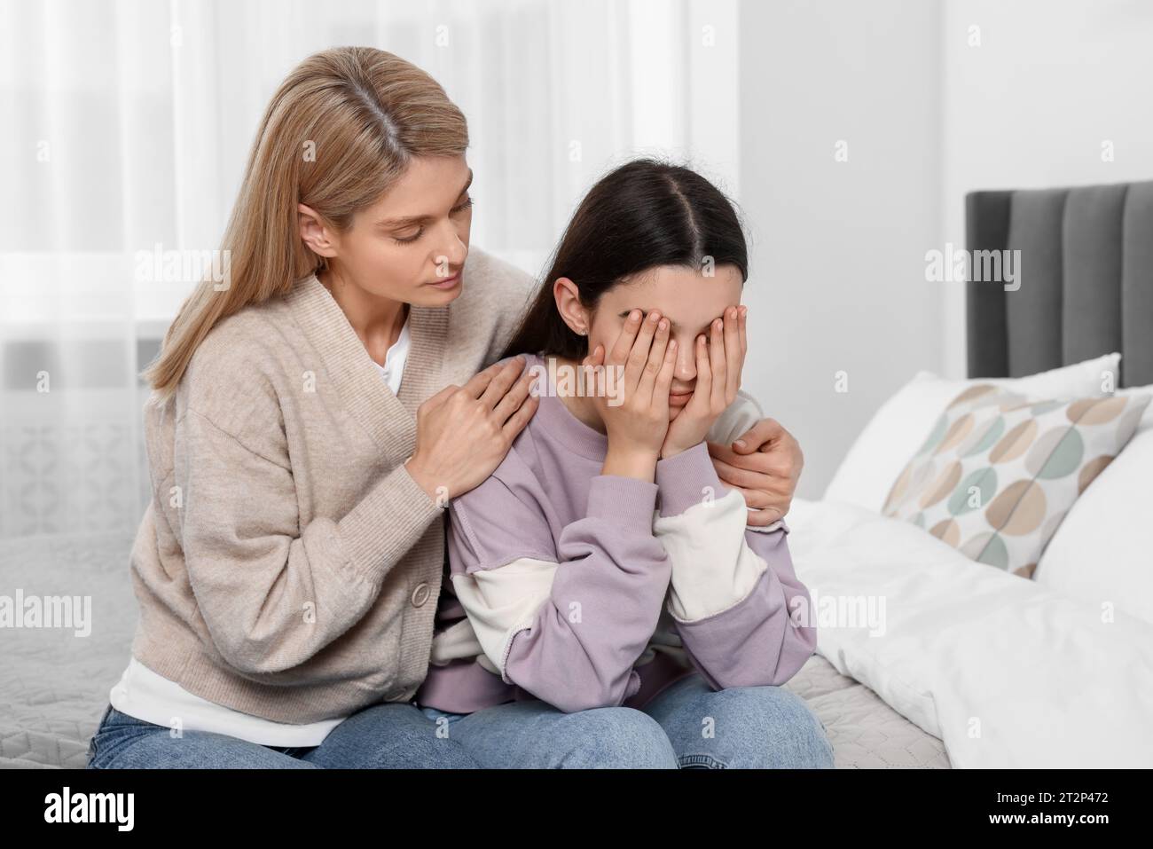 Mother consoling her upset daughter in bedroom. Teenager problems Stock ...