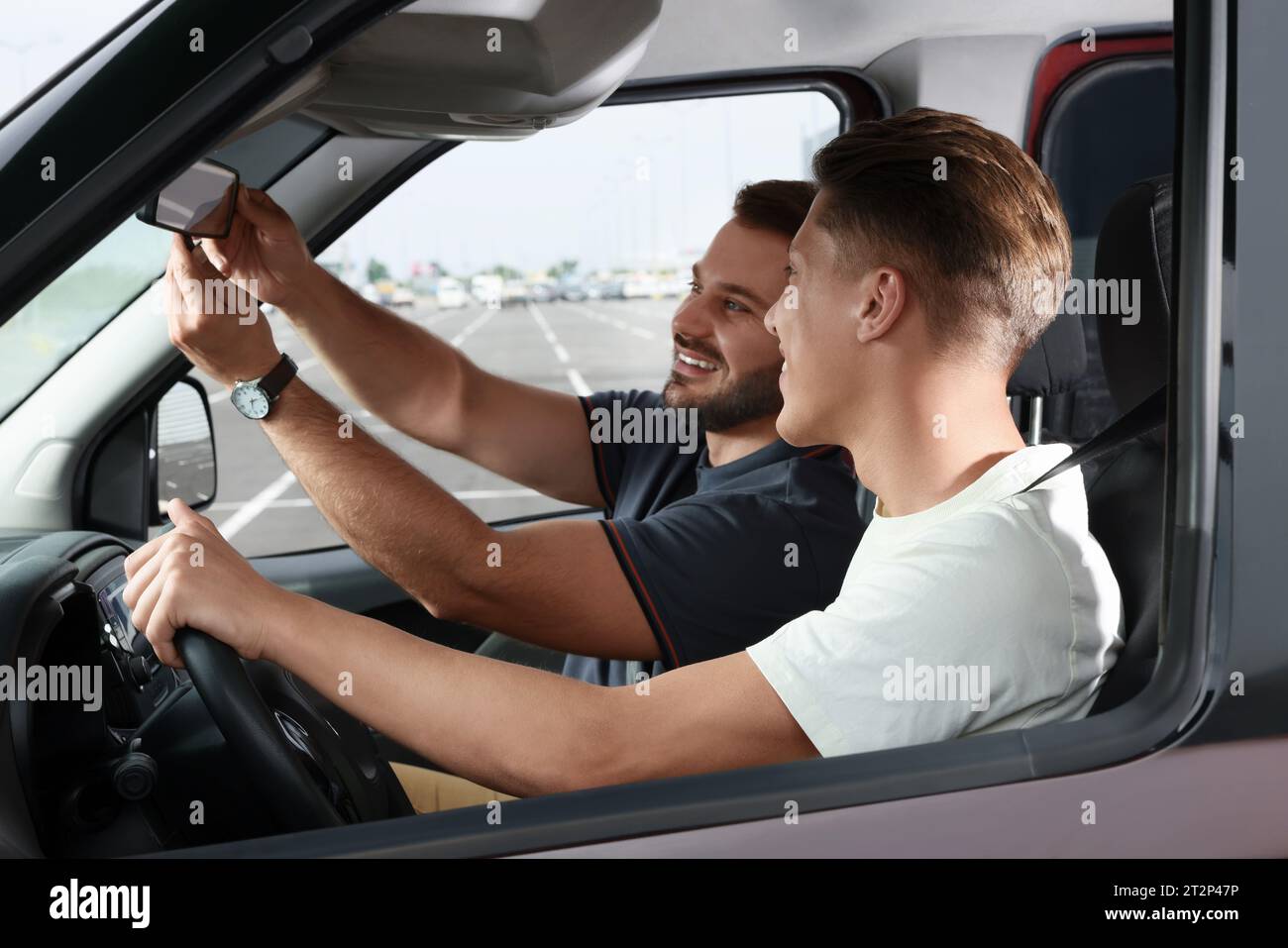 Driving school. Happy student during lesson with driving instructor in ...