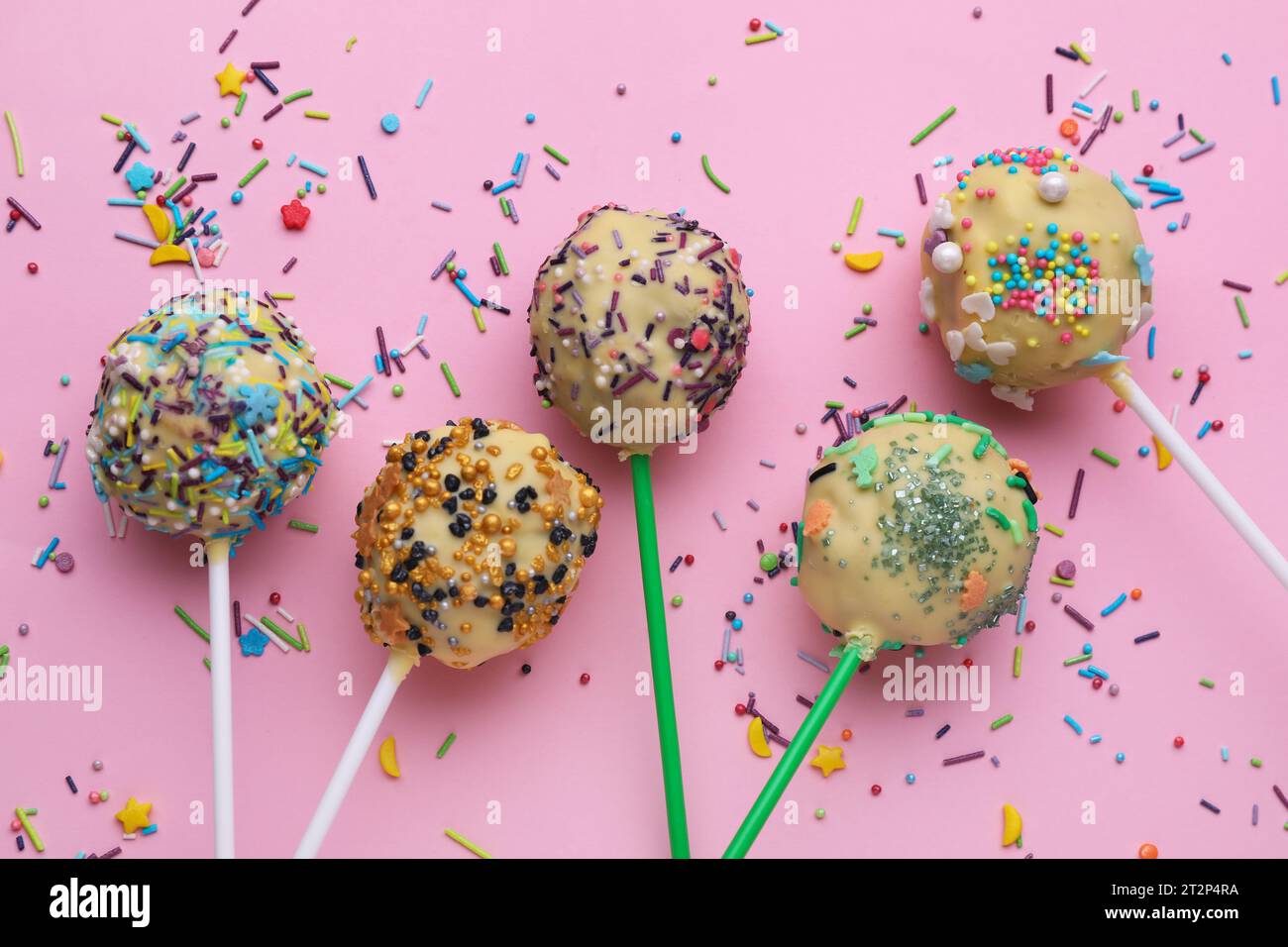 Delicious confectionery. Sweet cake pops and sprinkles on pale pink ...