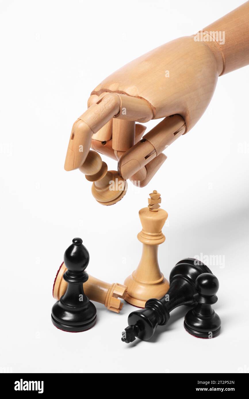 Robot holding pawn over other chess pieces on white background. Wooden ...