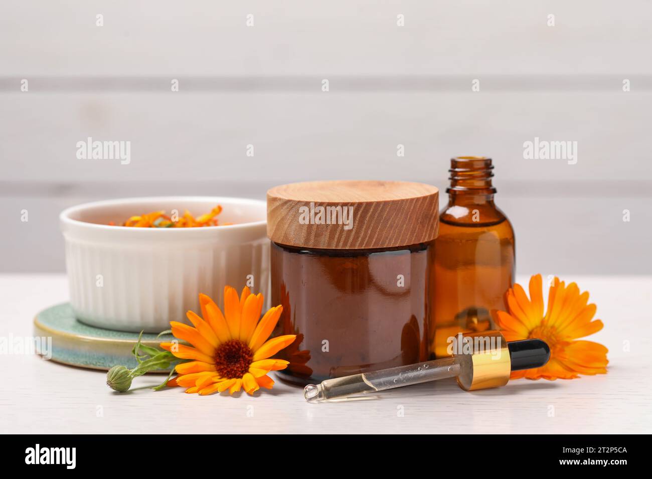 Different cosmetic products with beautiful calendula flowers on white ...