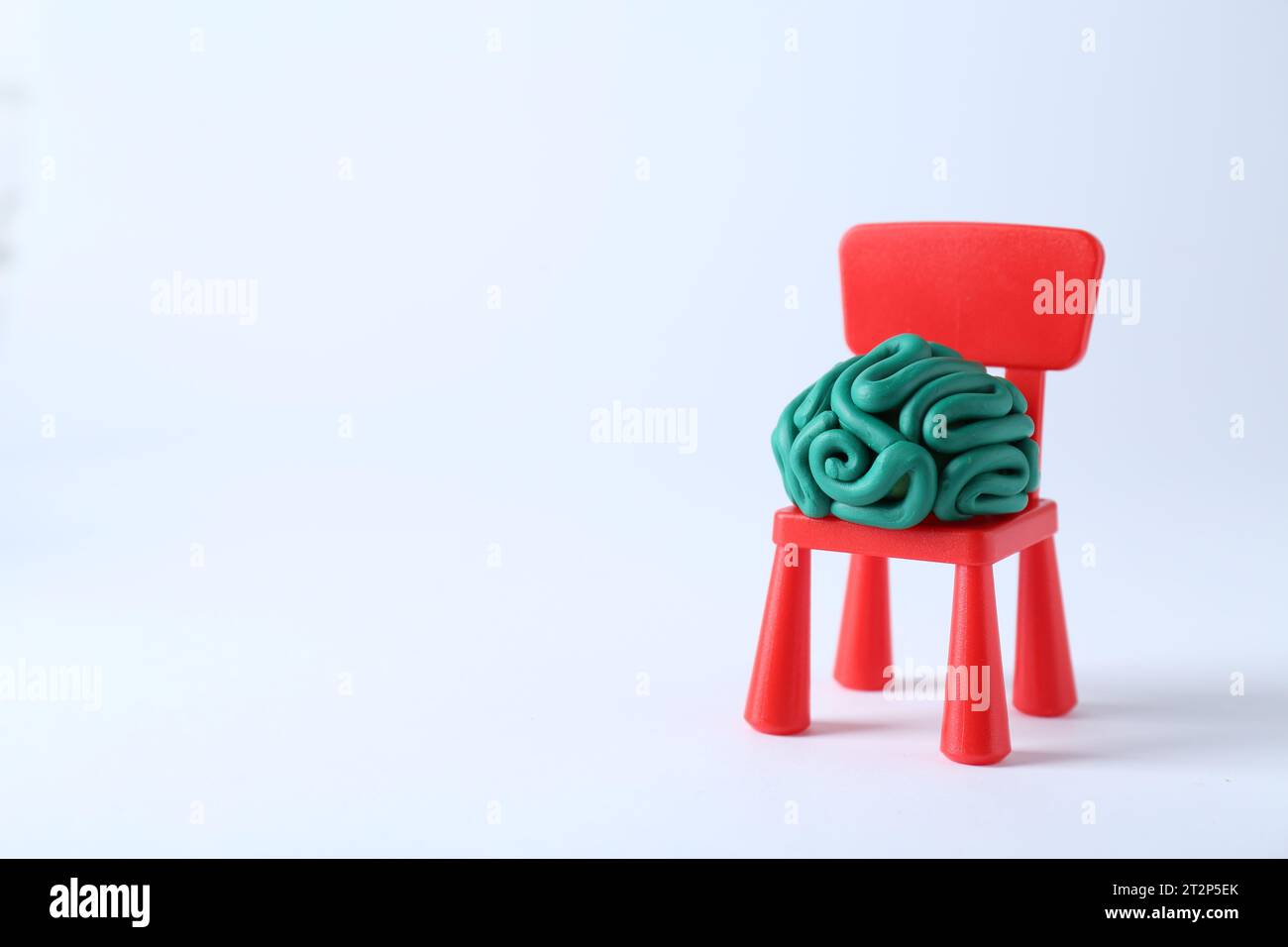 Brain made of plasticine on mini chair against white background. Space ...