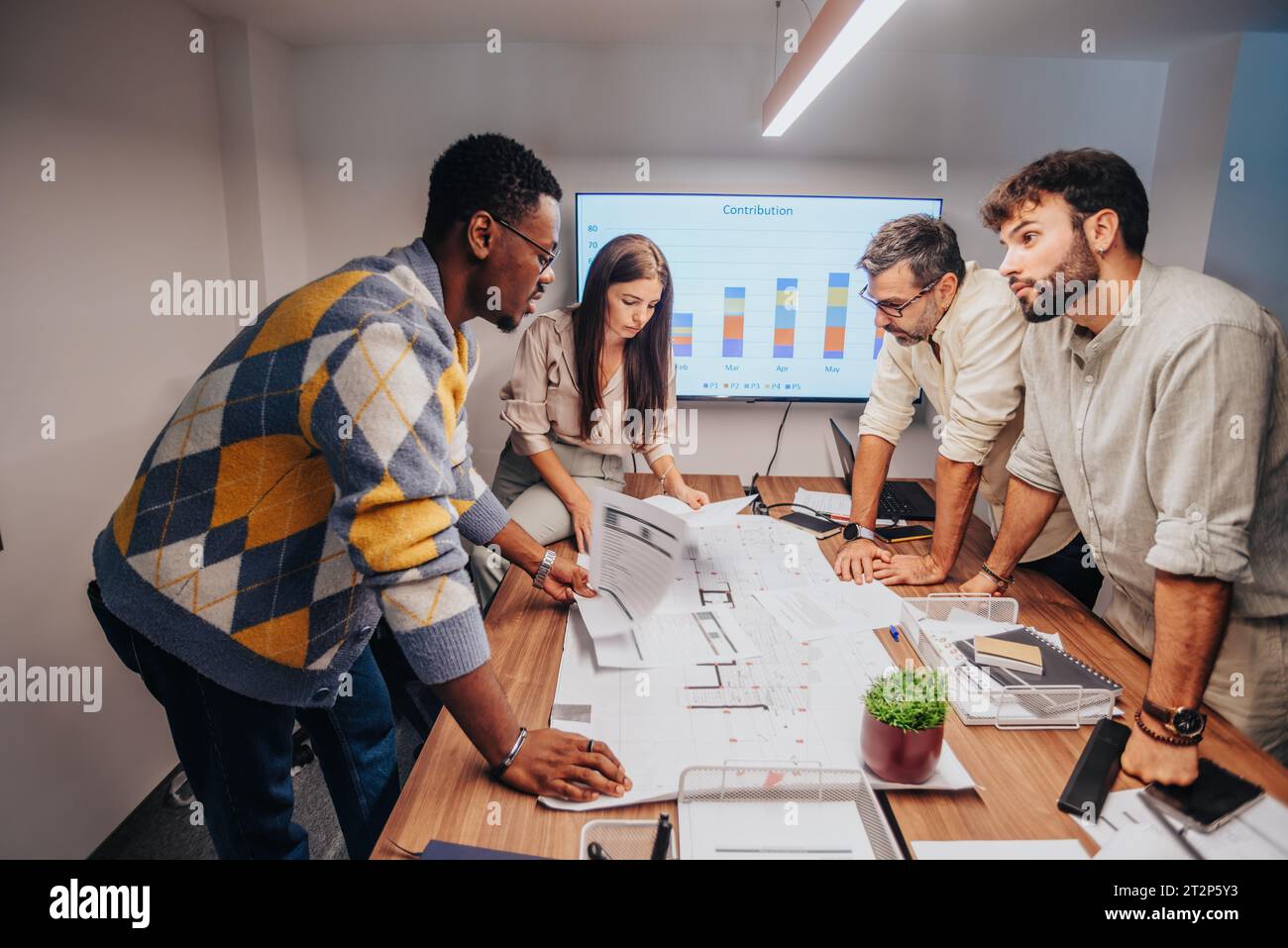 Multiracial team collaborates on architectural blueprint, discussing ...