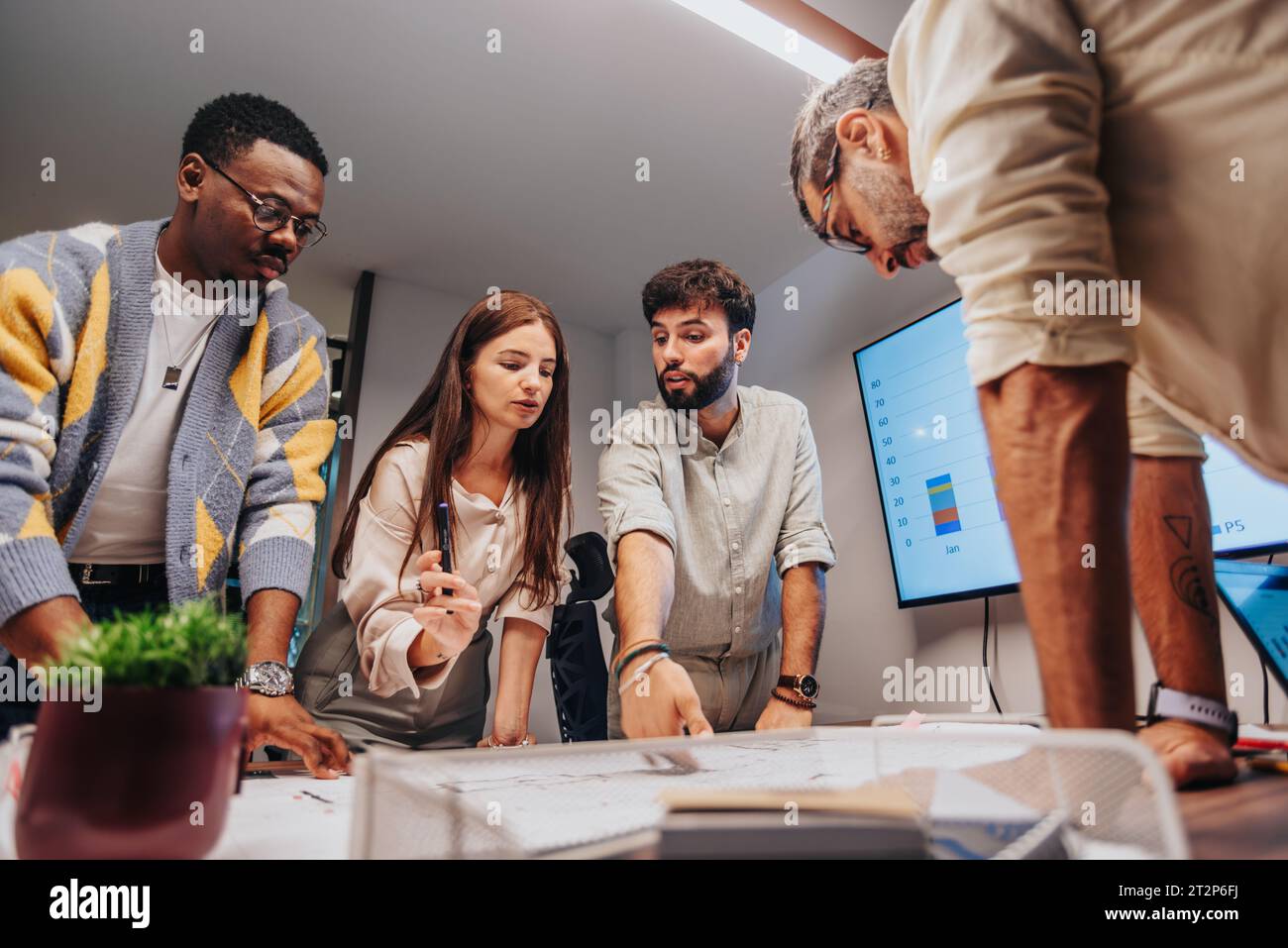 Multiracial Team of Architects Collaborating on Project Blueprint in ...