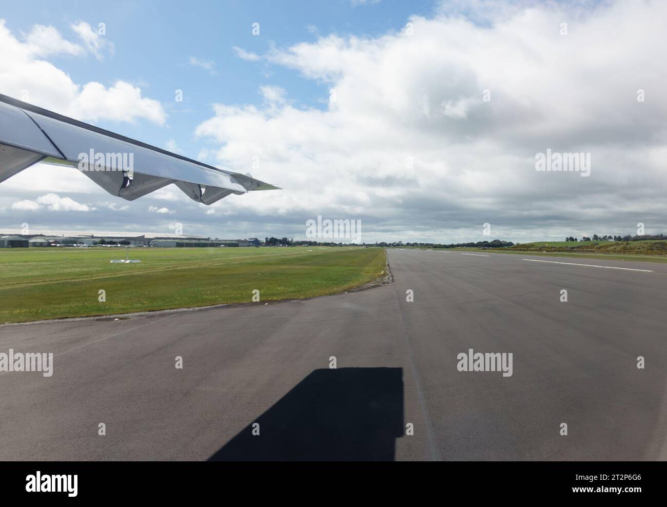 Outlook plane wing shadow on airport runway and clouds from window in ...