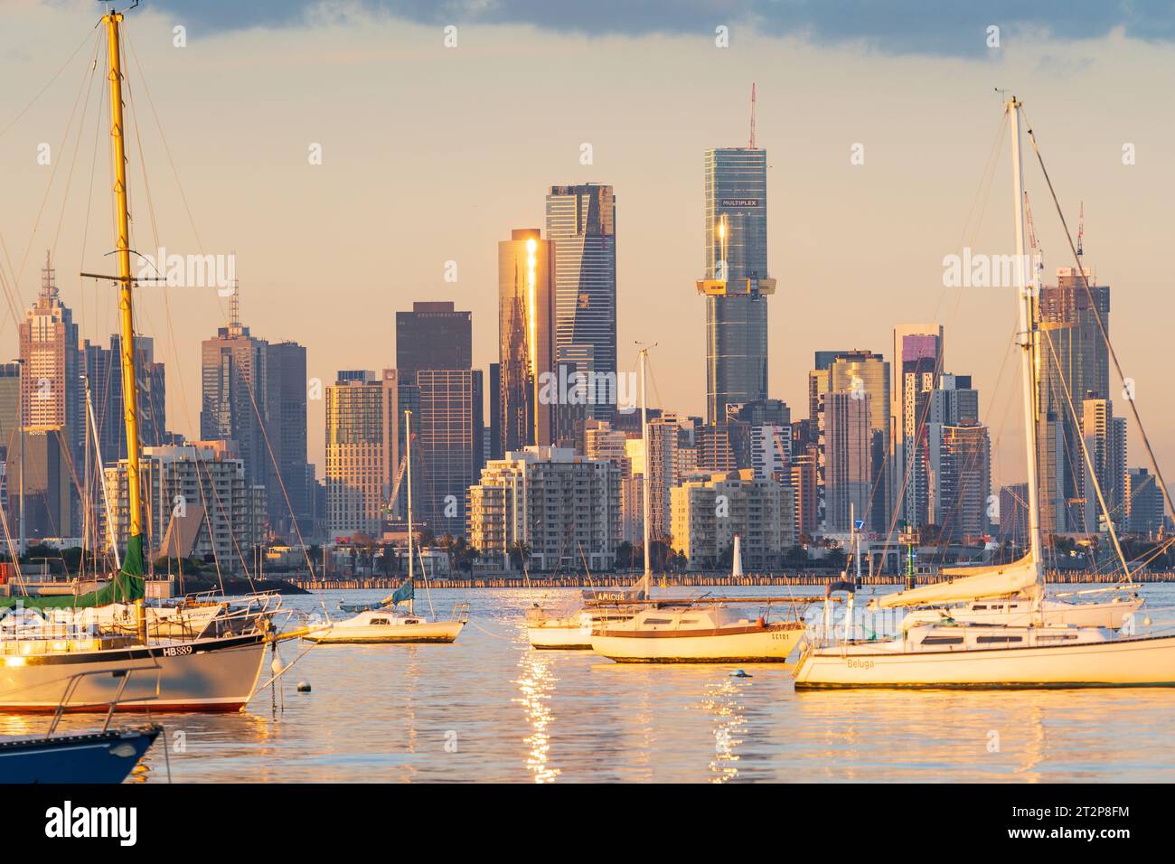 Distant view of yachts on a calm bay in front of a city skyline in late ...
