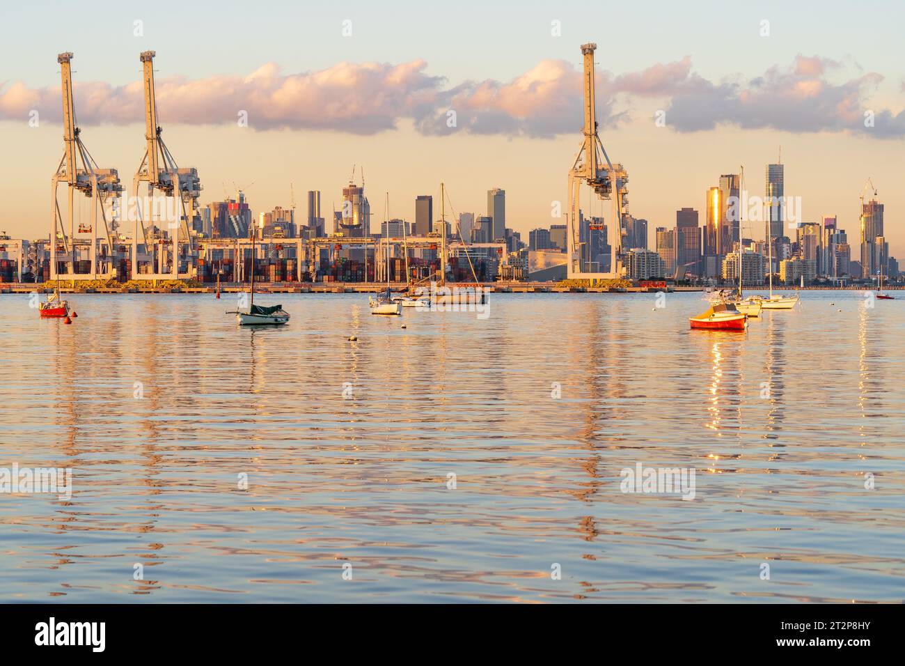View across a calm bay at boats and gantry cranes of the Port of ...