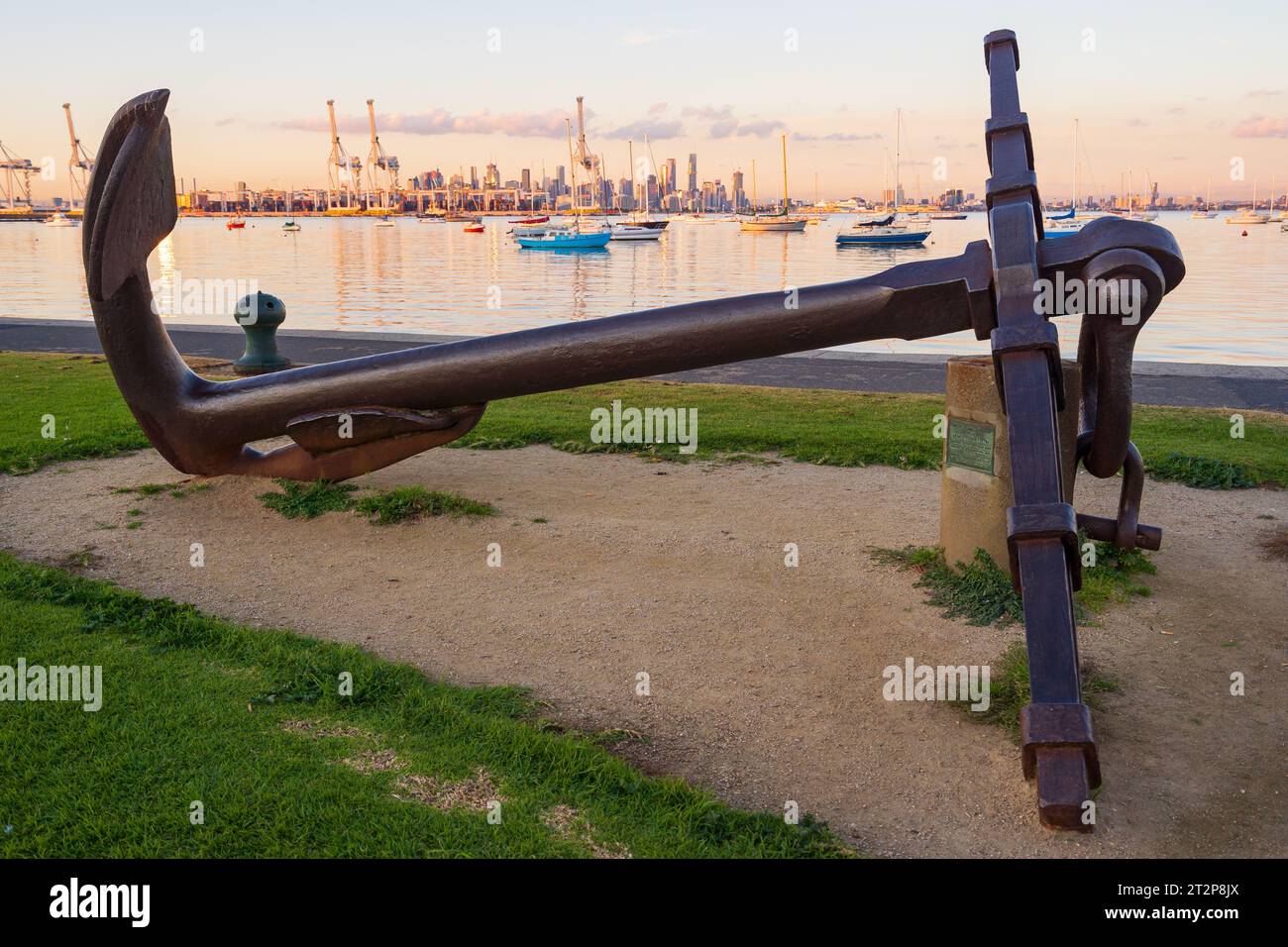 A large historic anchor lying in a waterfront reserve alongside a calm ...
