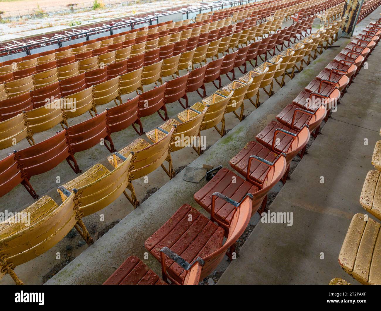 Old faded orange and yellow painted wooden seats at a abandoned a ...