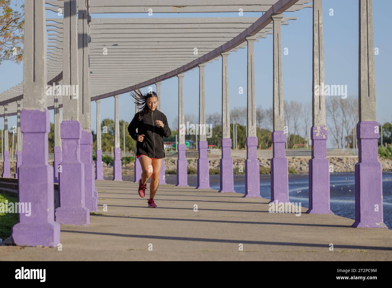 Latin girl runs by a pergola along the river bank Stock Photo - Alamy