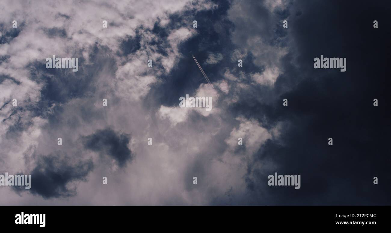 Dreamy white cloudscape beneath a deep blue sky and a passing jet plane ...