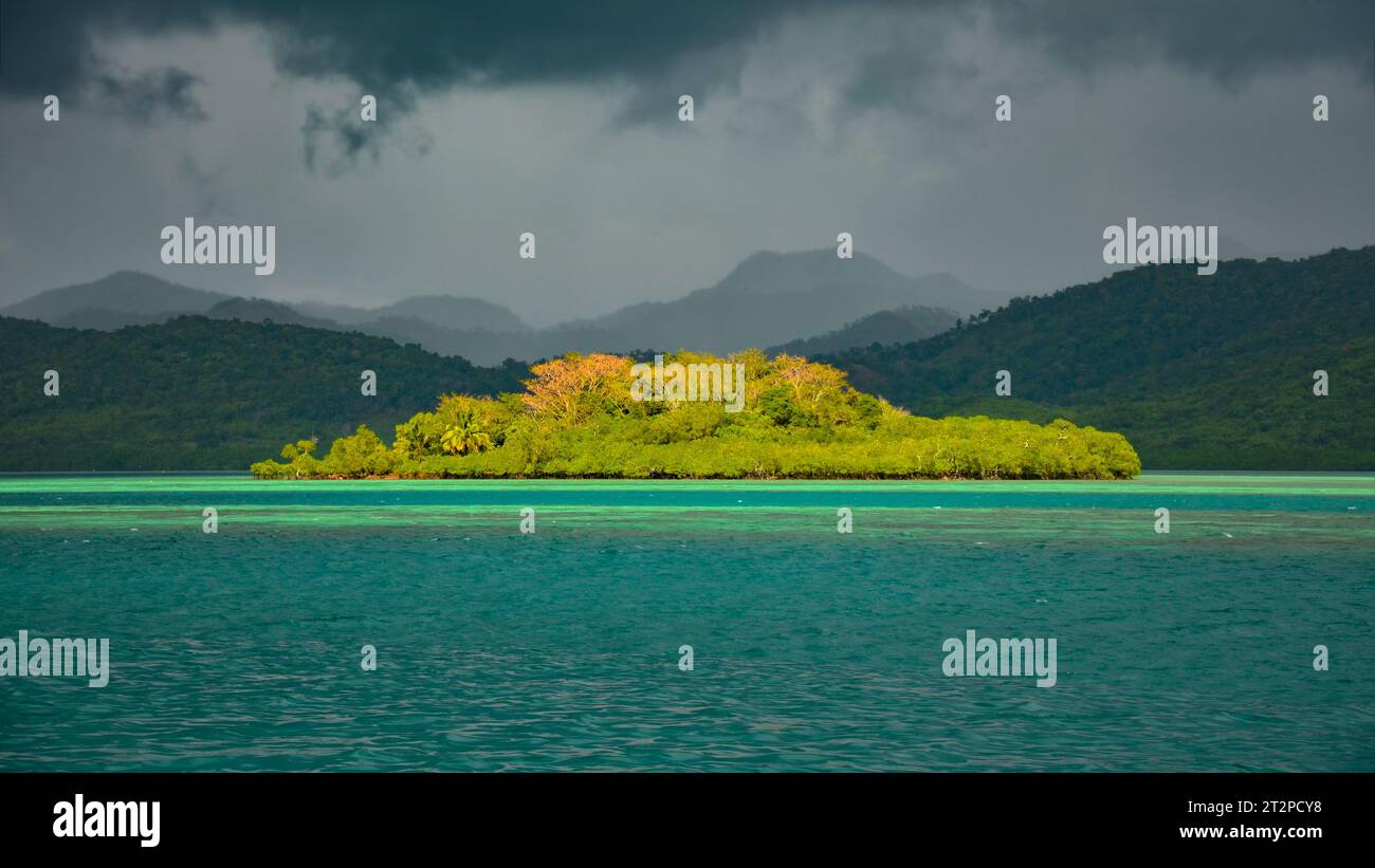 "Nice nook". Brightly lit by the sun a small tropical island in cloudy ...