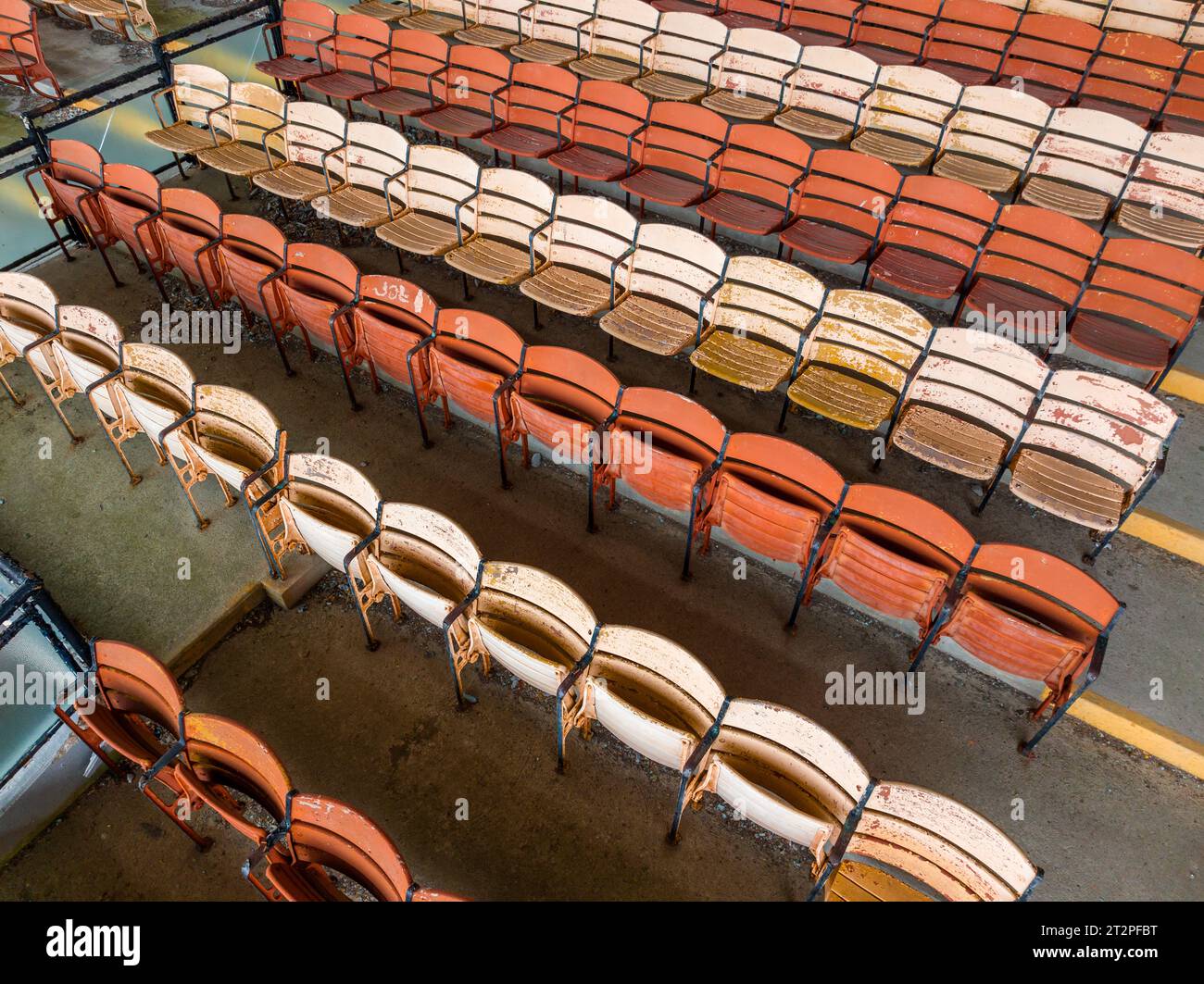 Old faded orange and yellow painted wooden seats at a abandoned a ...