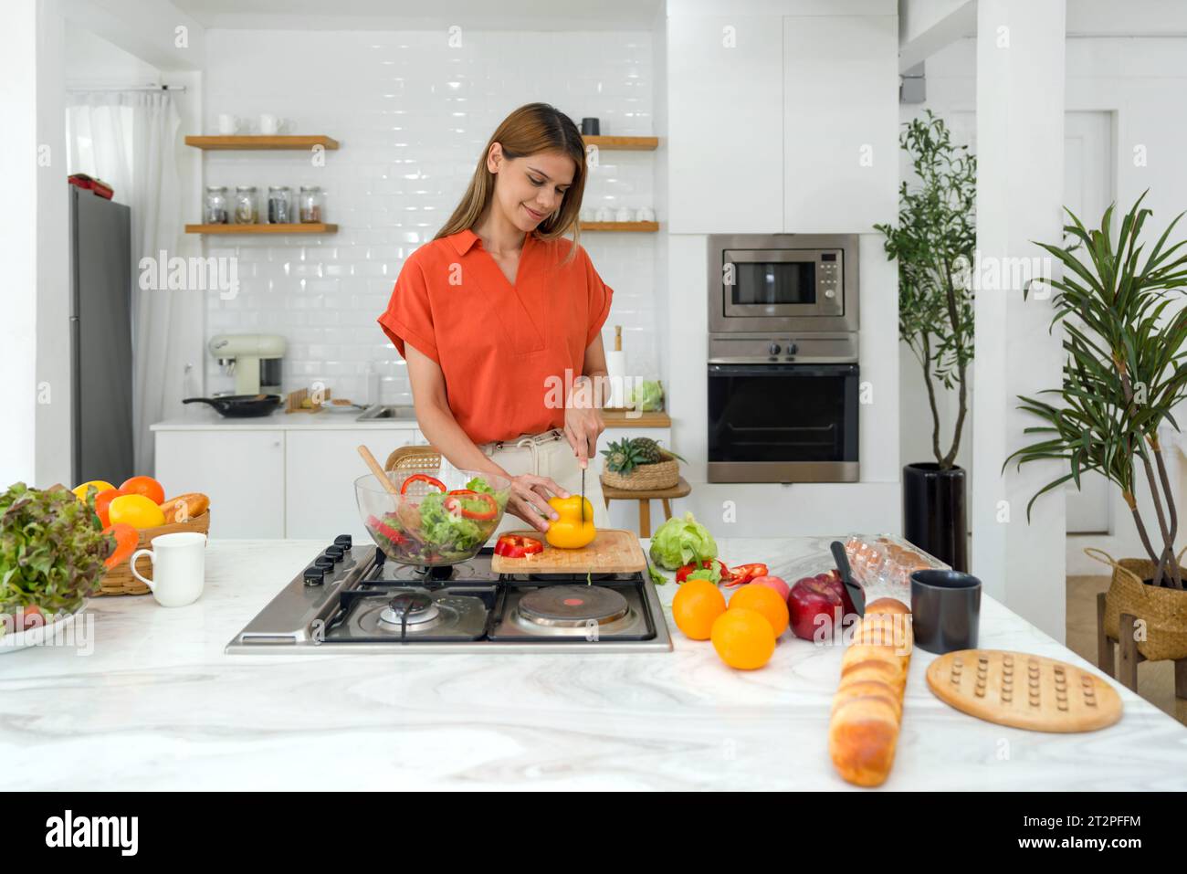 Young housewife enjoy making salad in a well-equipped, modern kitchen ...
