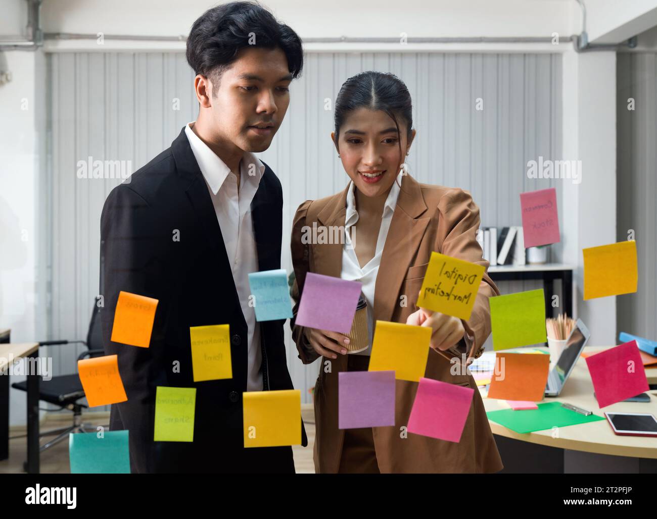 A professional man and woman stand together, engaged in a brainstorming ...