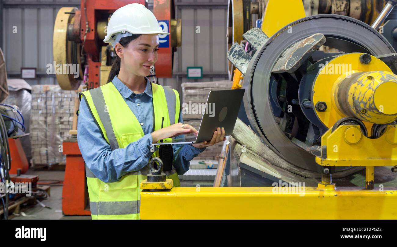A dedicated female engineer dressed in safety gear, holding laptop ...