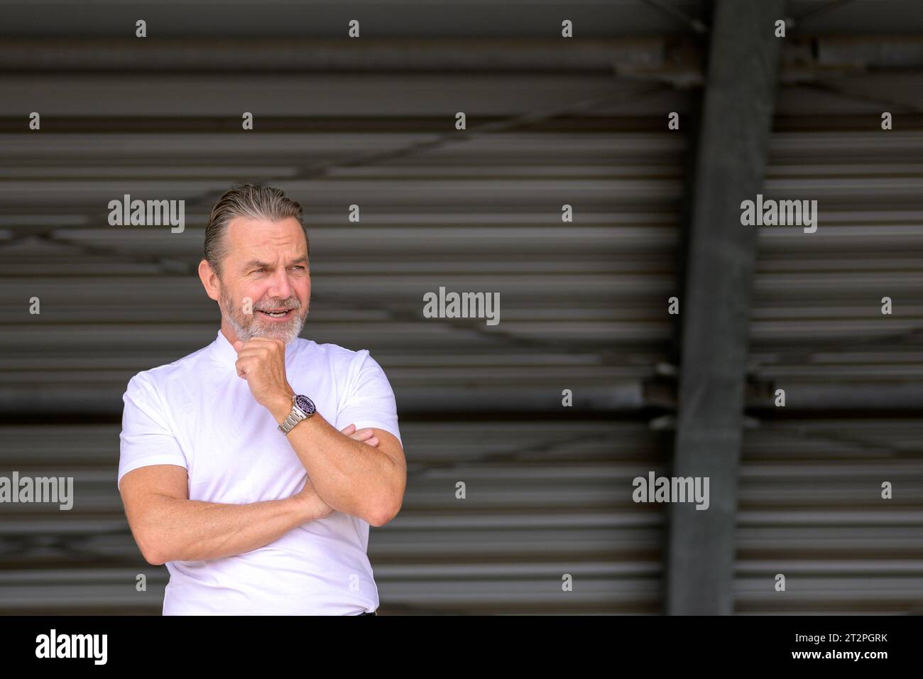 Side view of an attractive gray haired man with a white T-shirt has his ...