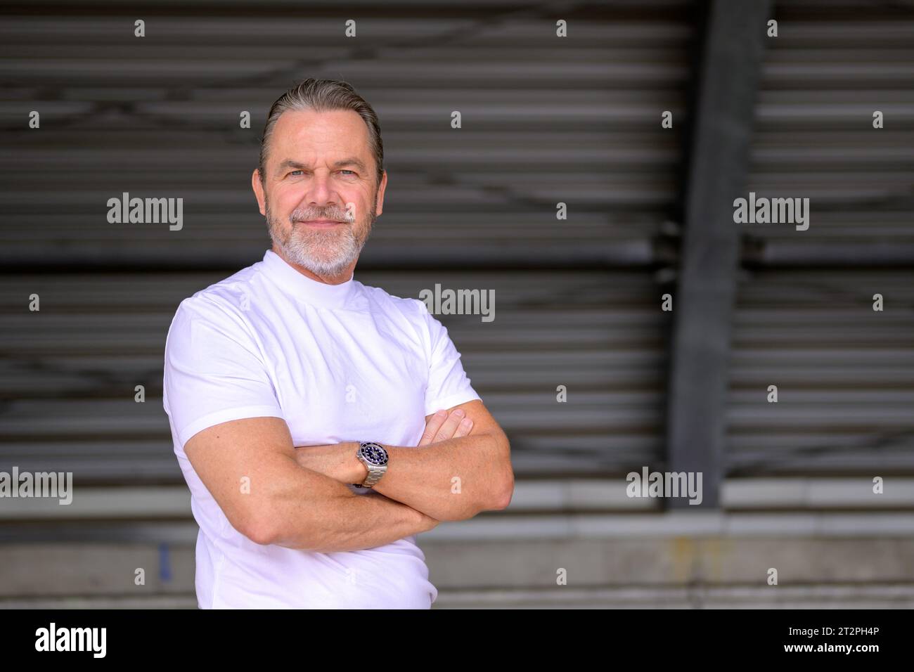 Side view of an attractive gray haired man with a white T-shirt has his ...
