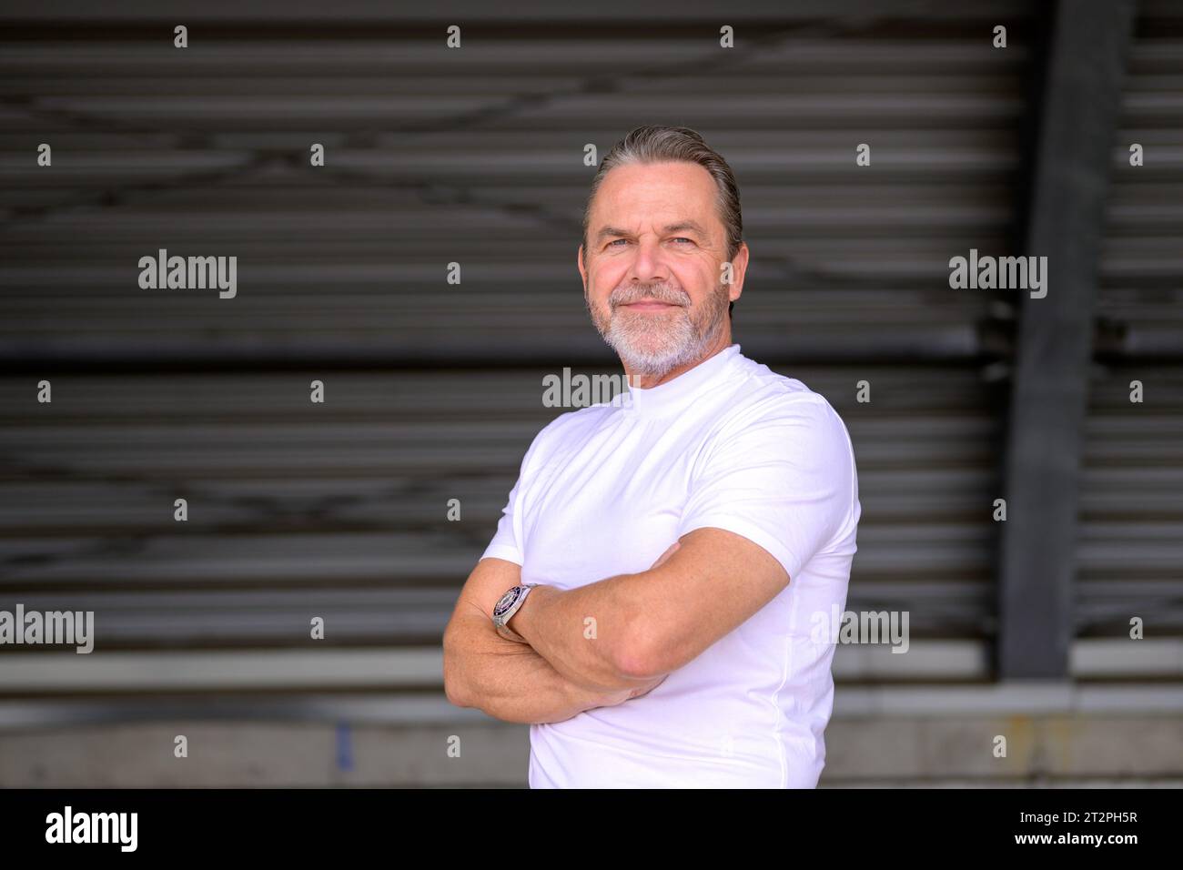 Side view of an attractive gray haired man with a white T-shirt has his ...
