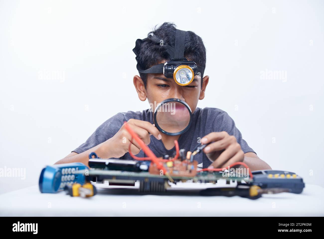 Young schoolboy using magnifying glass working on a computer ...