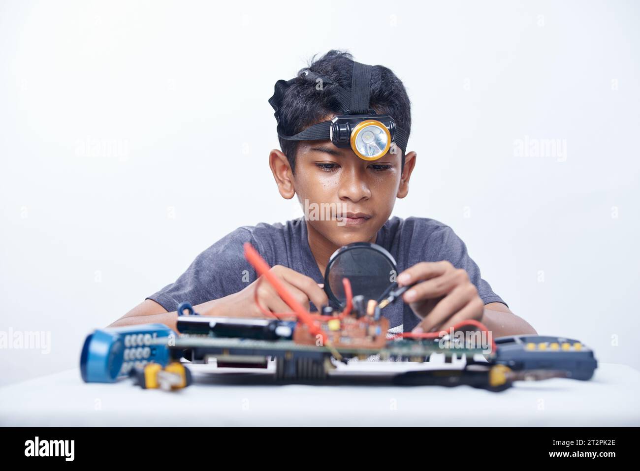 Young schoolboy using magnifying glass working on a computer ...