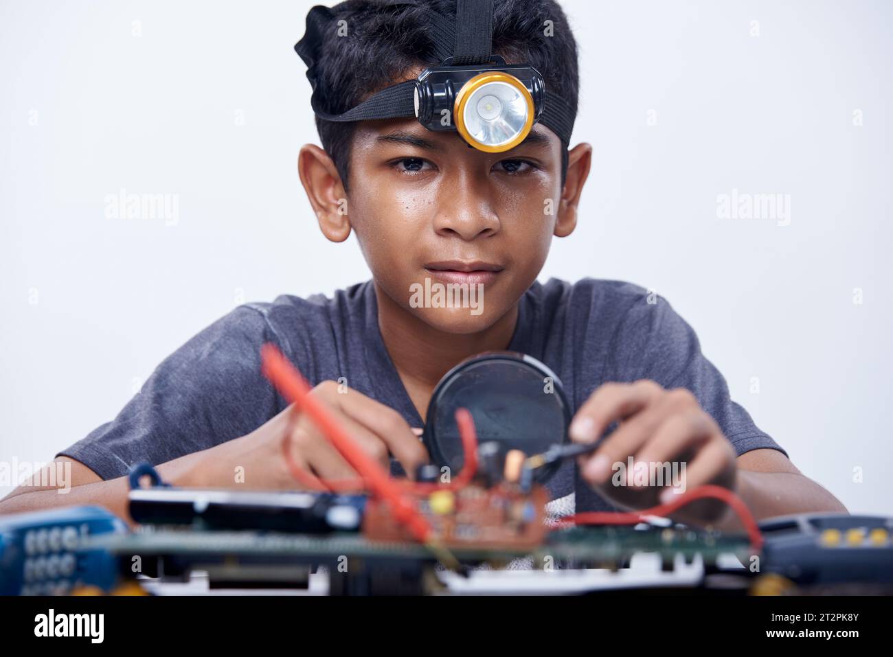 Young schoolboy using magnifying glass working on a computer ...