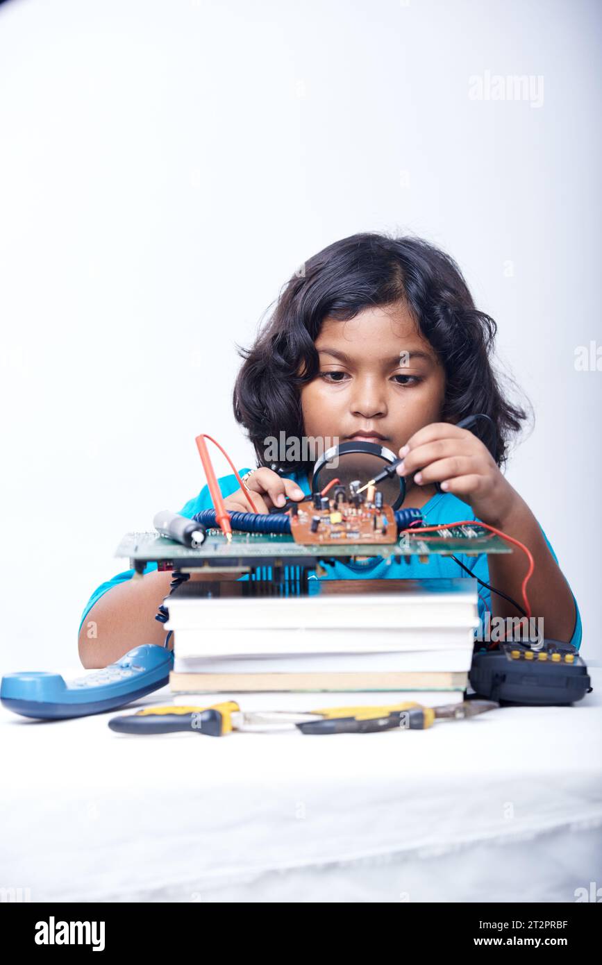 Student girl using magnifying glass working on a computer motherboard ...