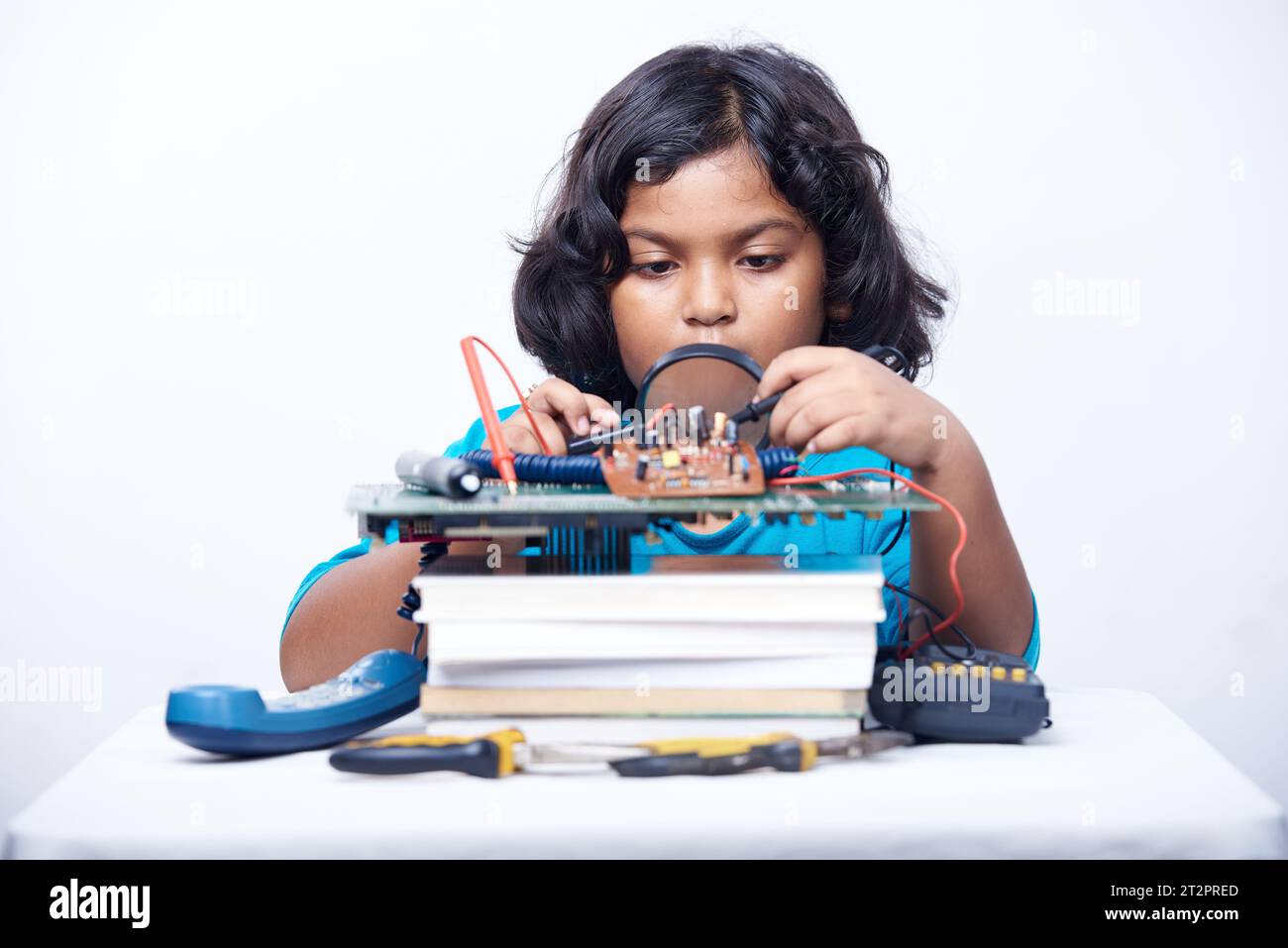 Student girl using magnifying glass working on a computer motherboard ...