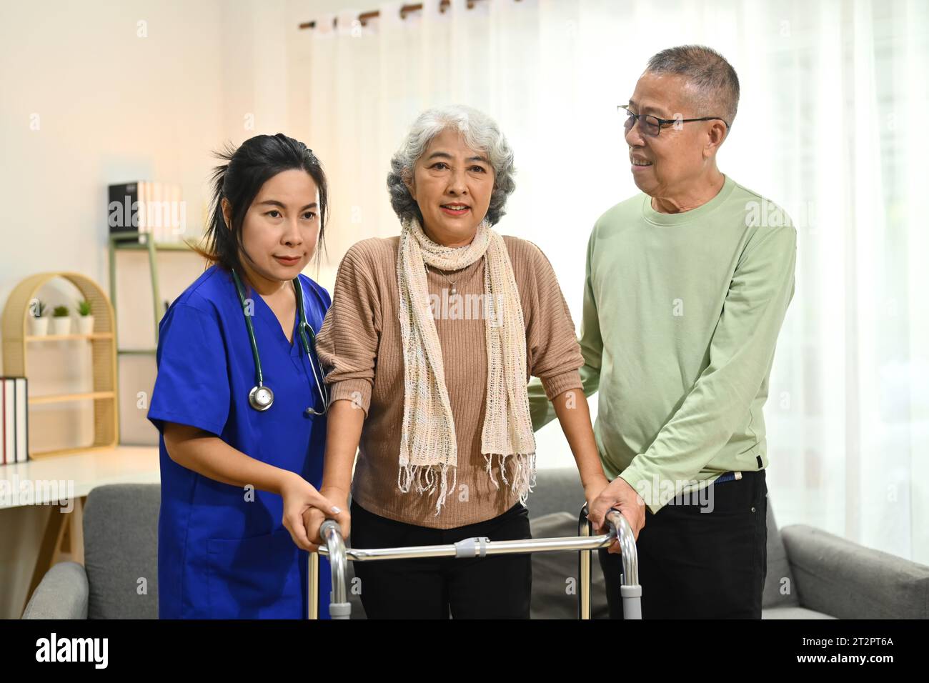 Positive female caregiver helping senior woman walking with walker ...