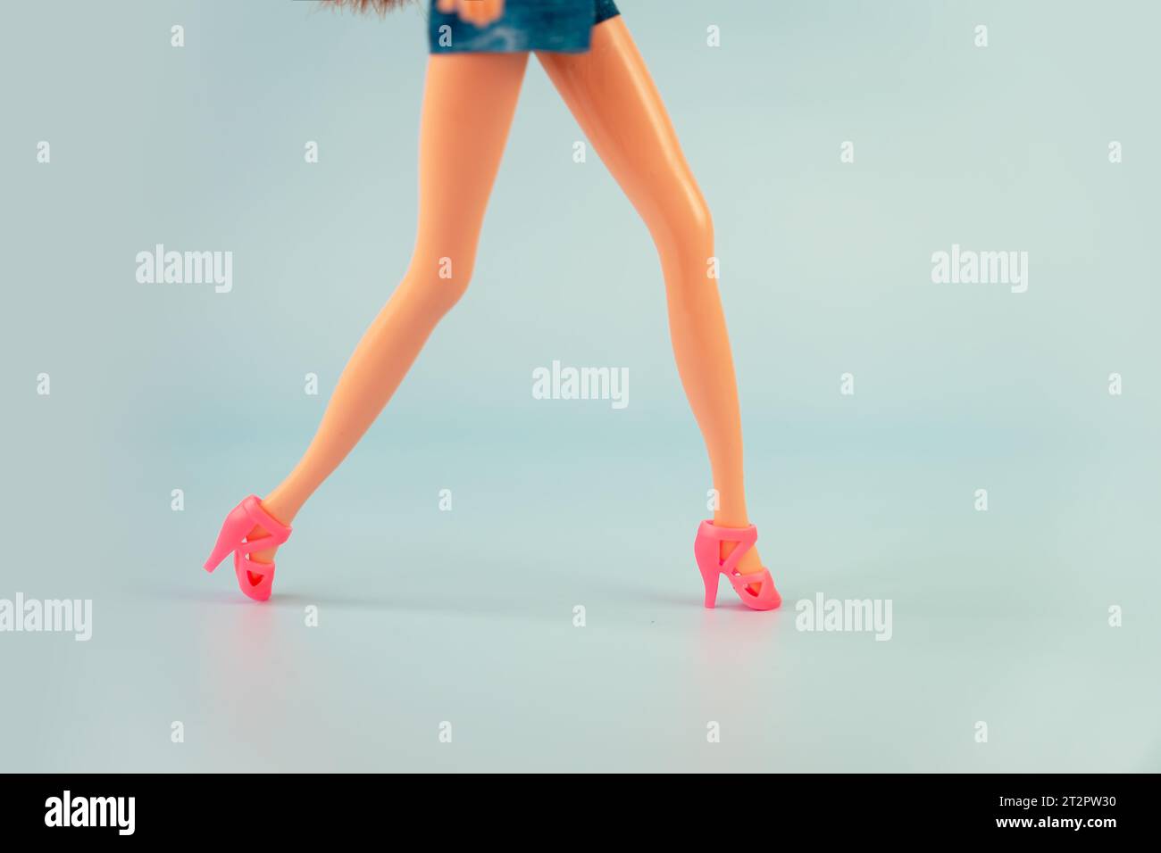Plastic doll legs in toy shoes on a blue background. educational games ...