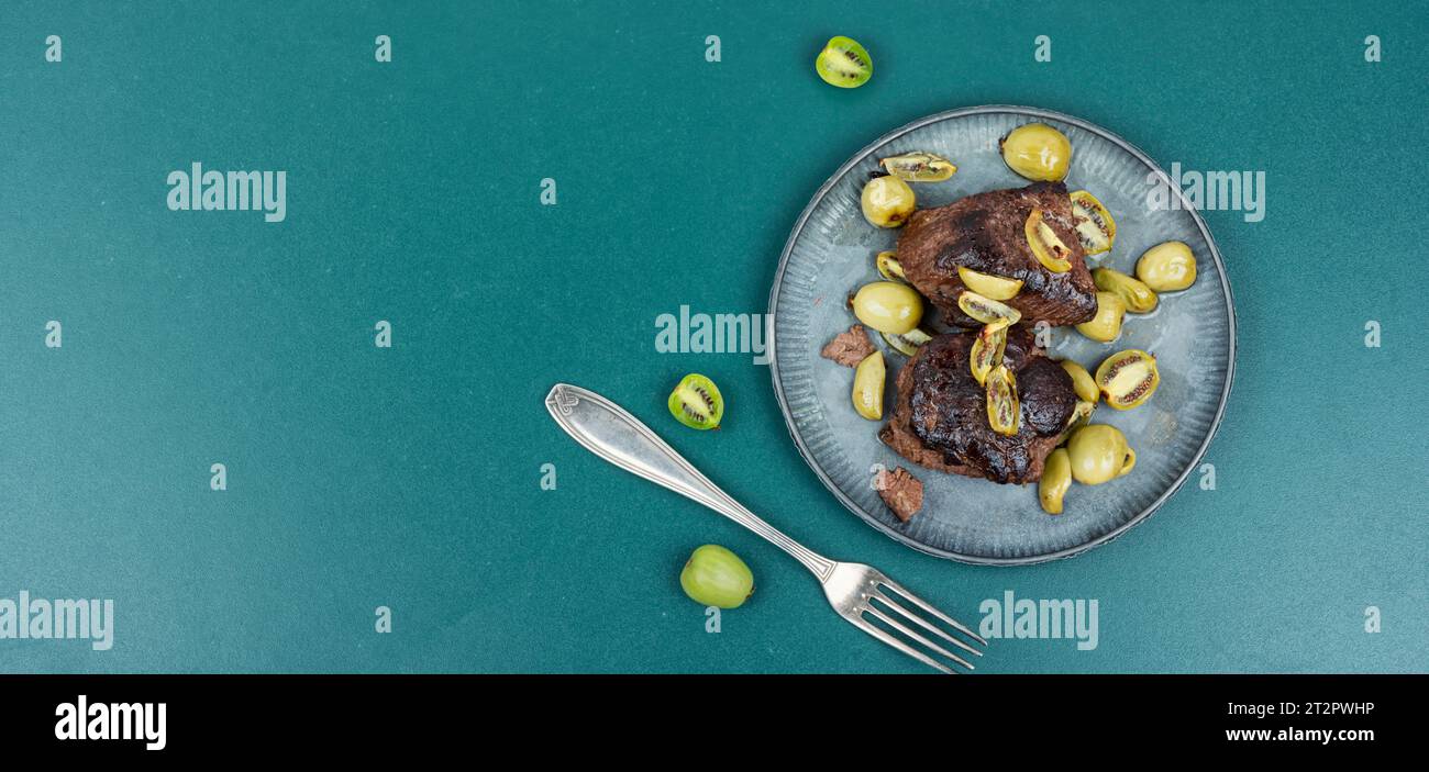 Roasted ostrich steak and mini kiwi on a plate Stock Photo - Alamy