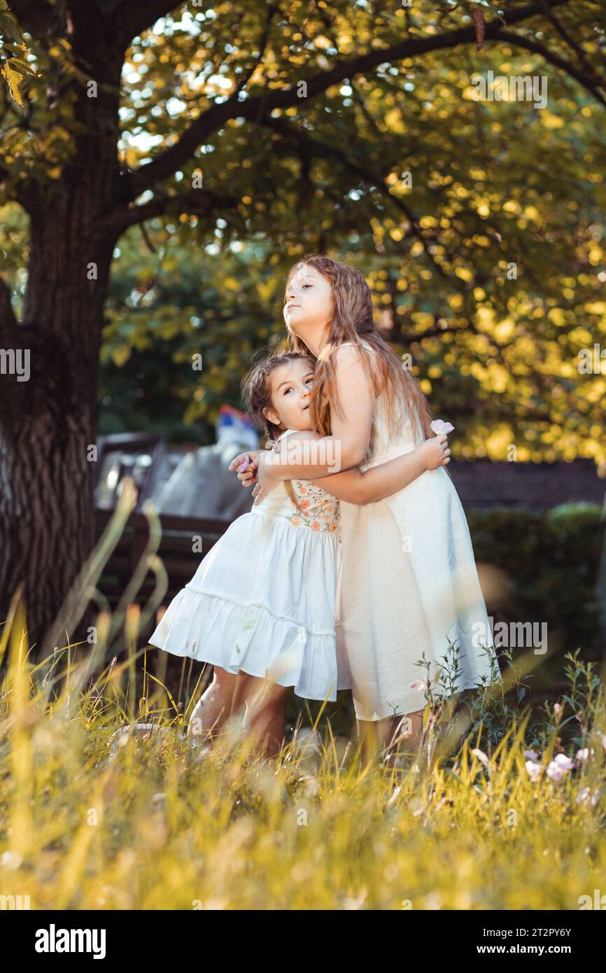 Two little girls, sisters in white dresses hugging Stock Photo - Alamy