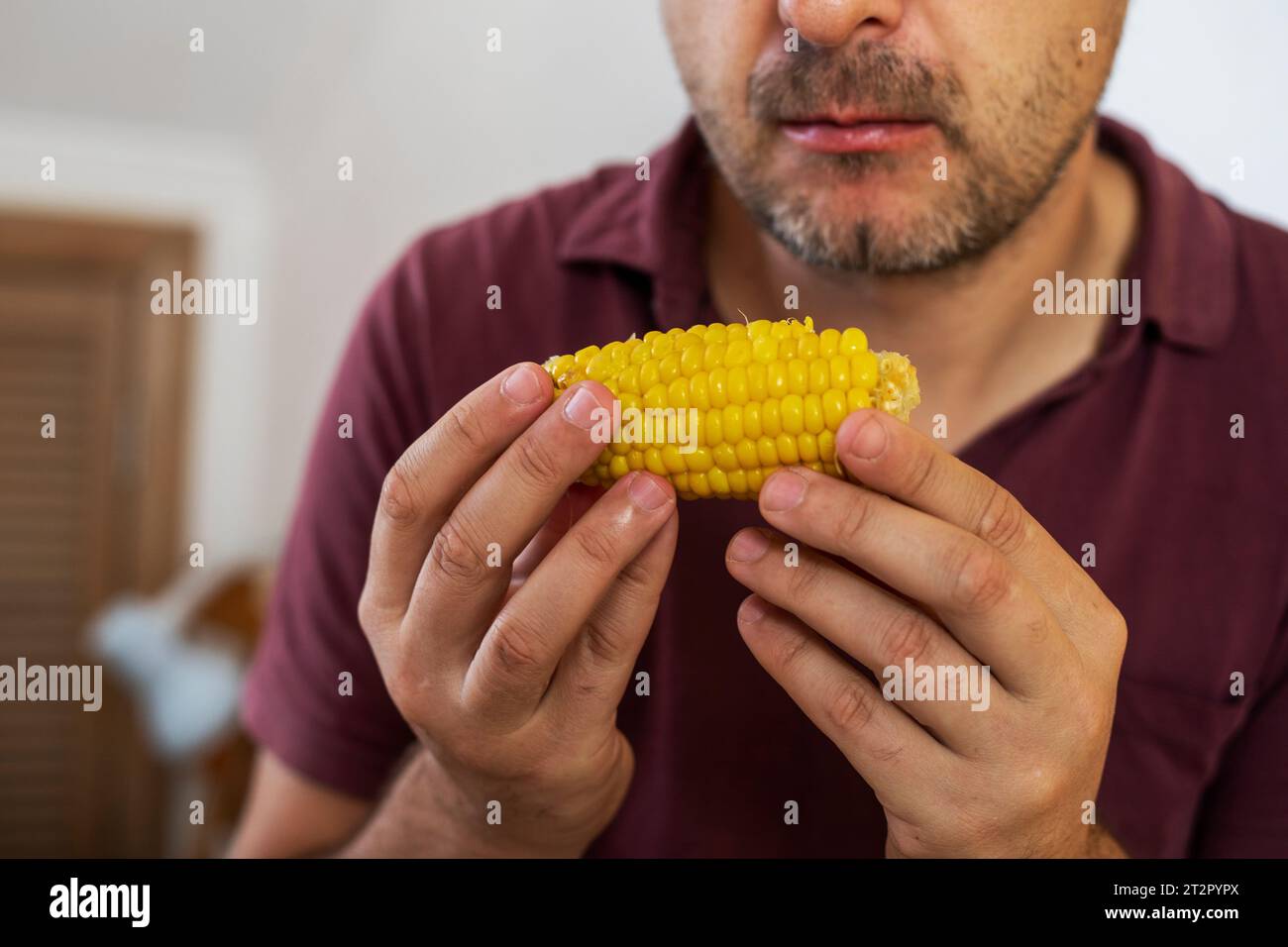 man bites off a piece of sweet corn with his teeth Stock Photo - Alamy