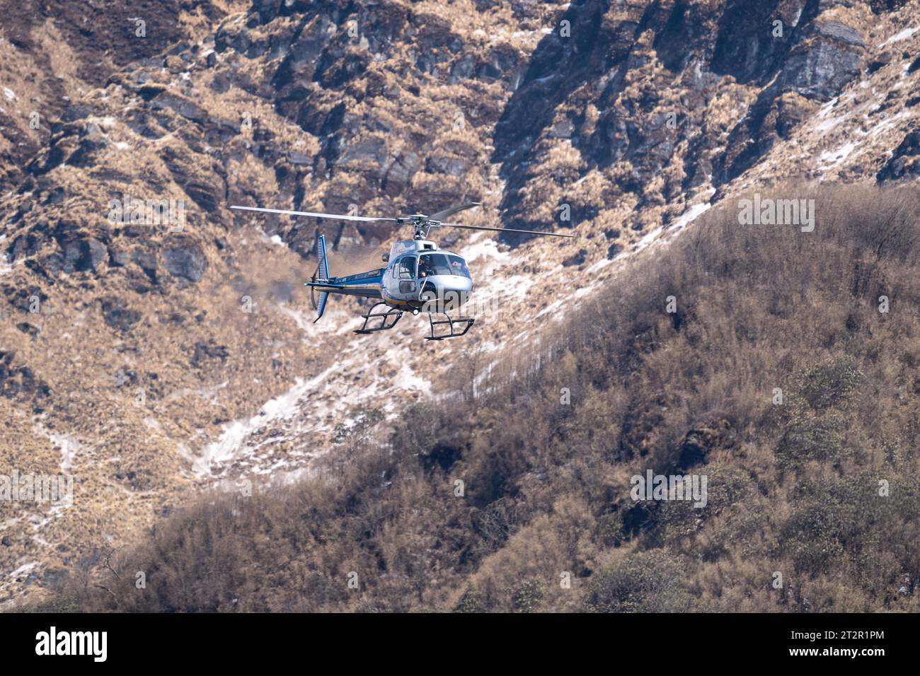 A helicopter skimming over a mountain ridge in the Himalayan Mountains ...