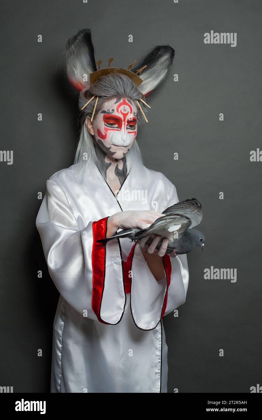 Rabbit woman with creative Halloween makeup hugging bird pigeon on ...