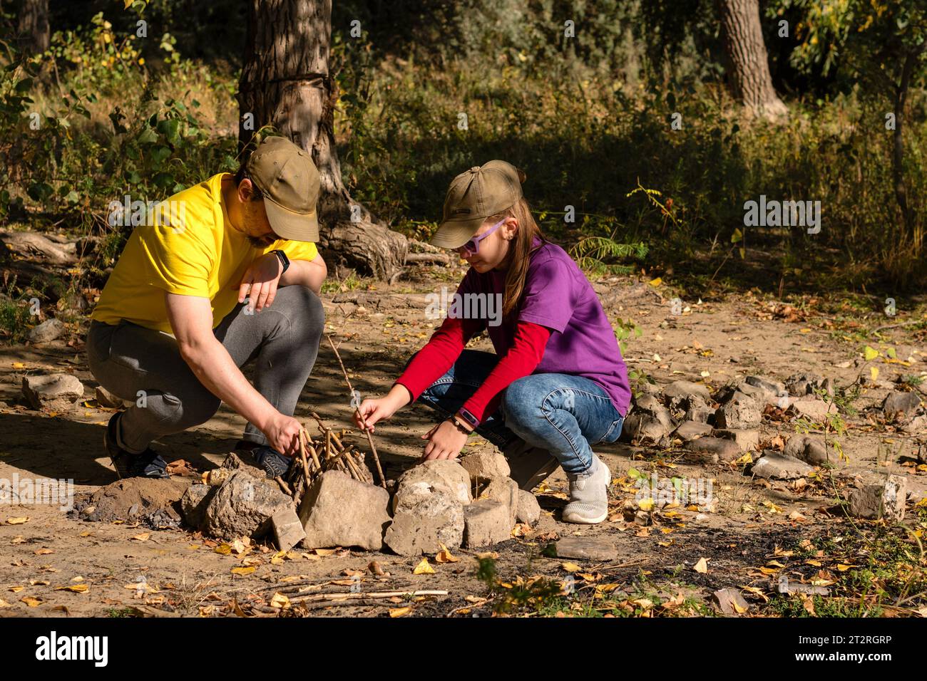 Dad and daughter make fire outdoors to cook food on camping trip ...