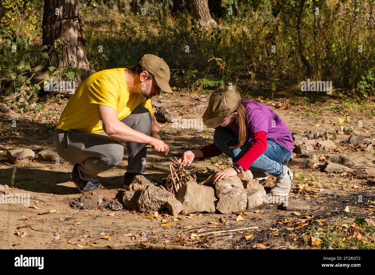 Dad and daughter make fire outdoors to cook food on camping trip ...