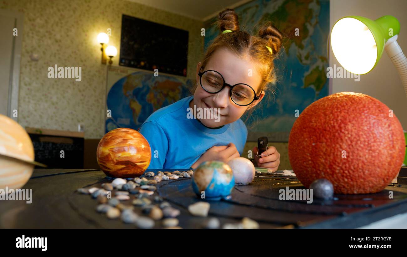 A gleeful young girl with quirky glasses and buns meticulously arranges ...