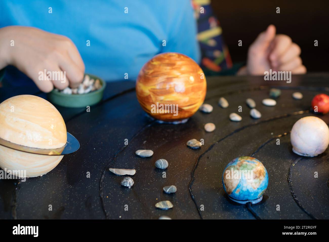 Close-up view of painted planets being assembled for a detailed solar ...