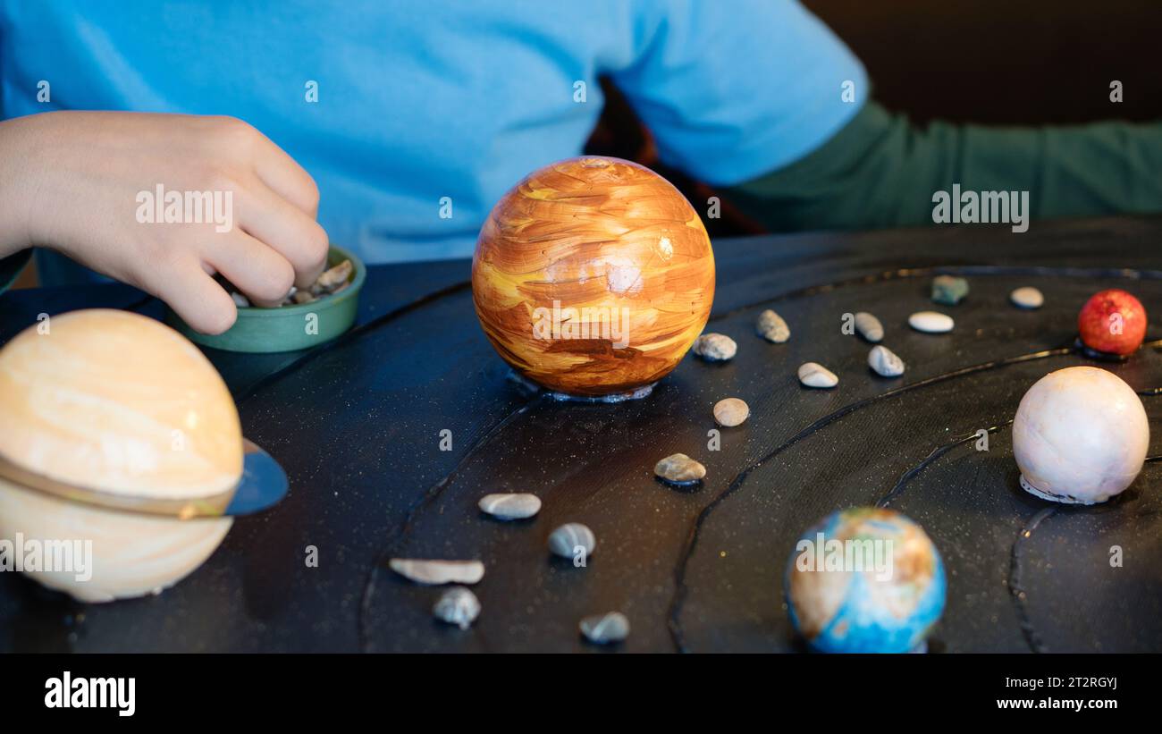 Close-up view of painted planets being assembled for a detailed solar ...