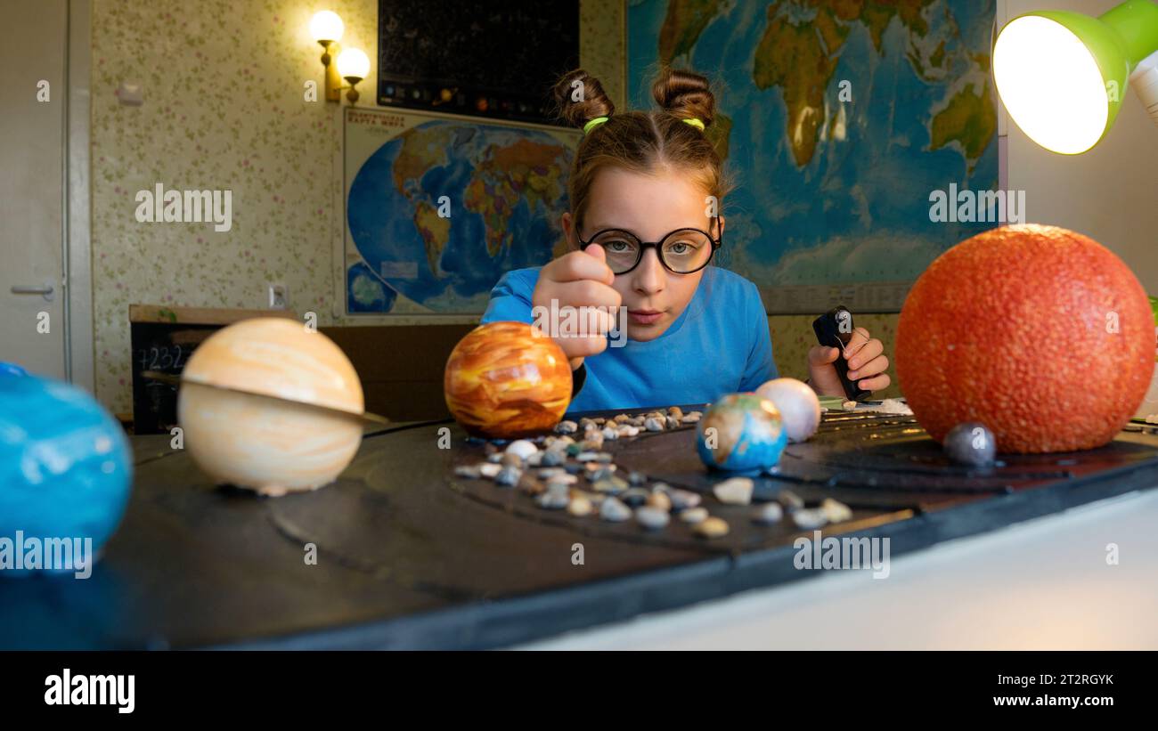 A gleeful young girl with quirky glasses and buns meticulously arranges ...