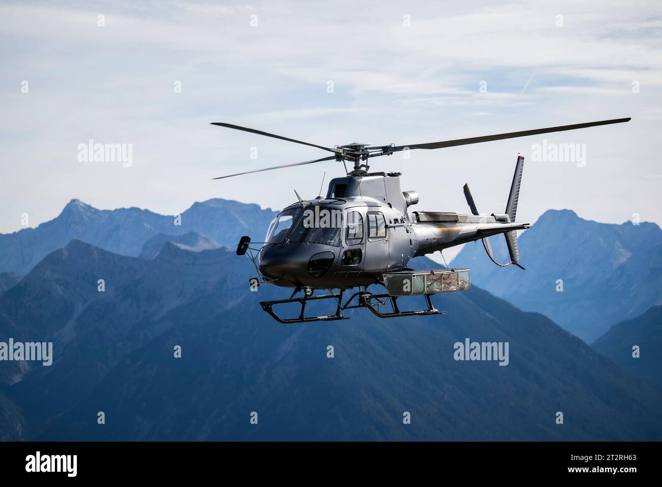 Dark gray cargo helicopter with accessories basket on the side flies in ...