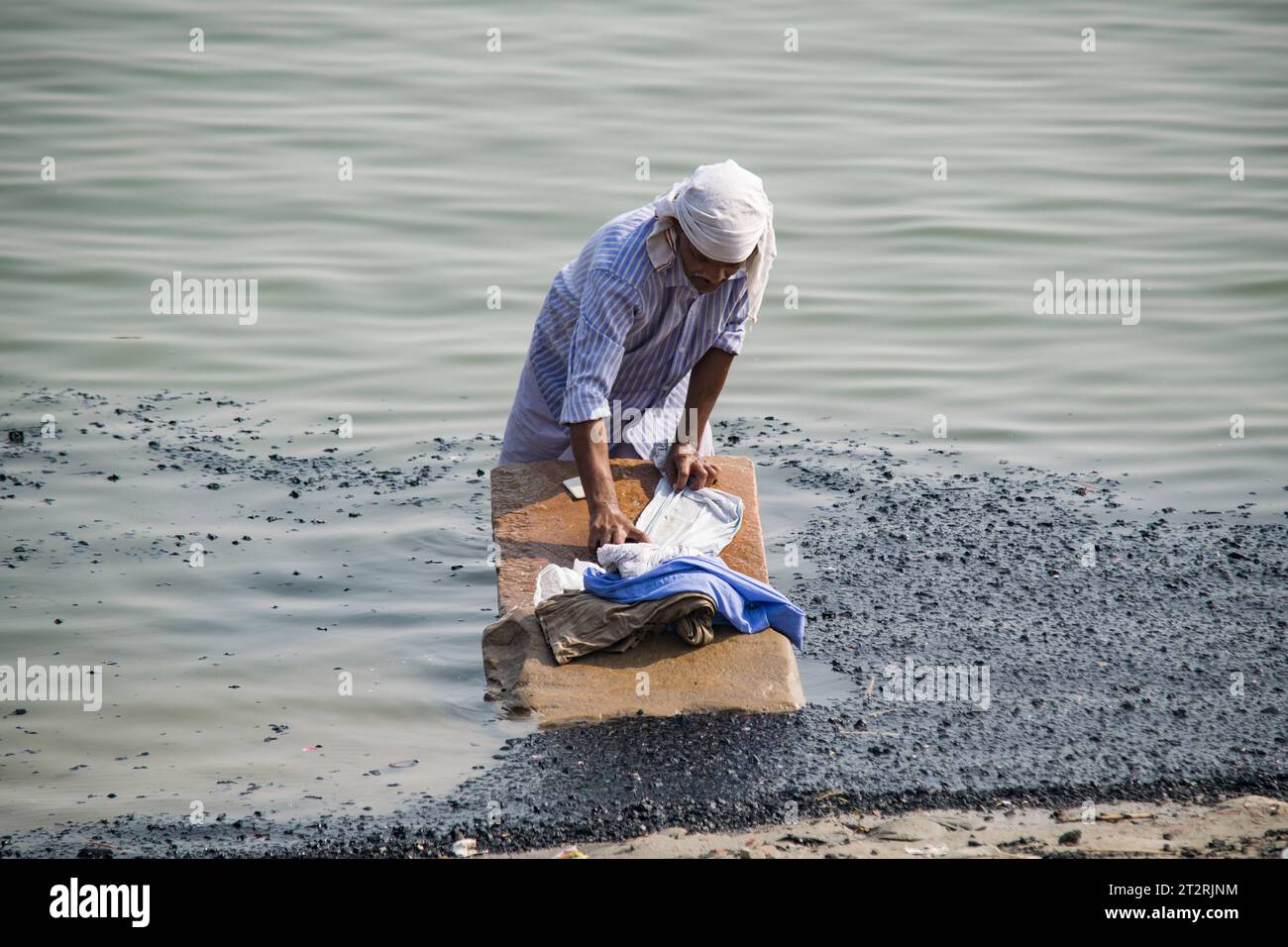Man washing clothes at Ganges river in Varanasi Stock Photo - Alamy