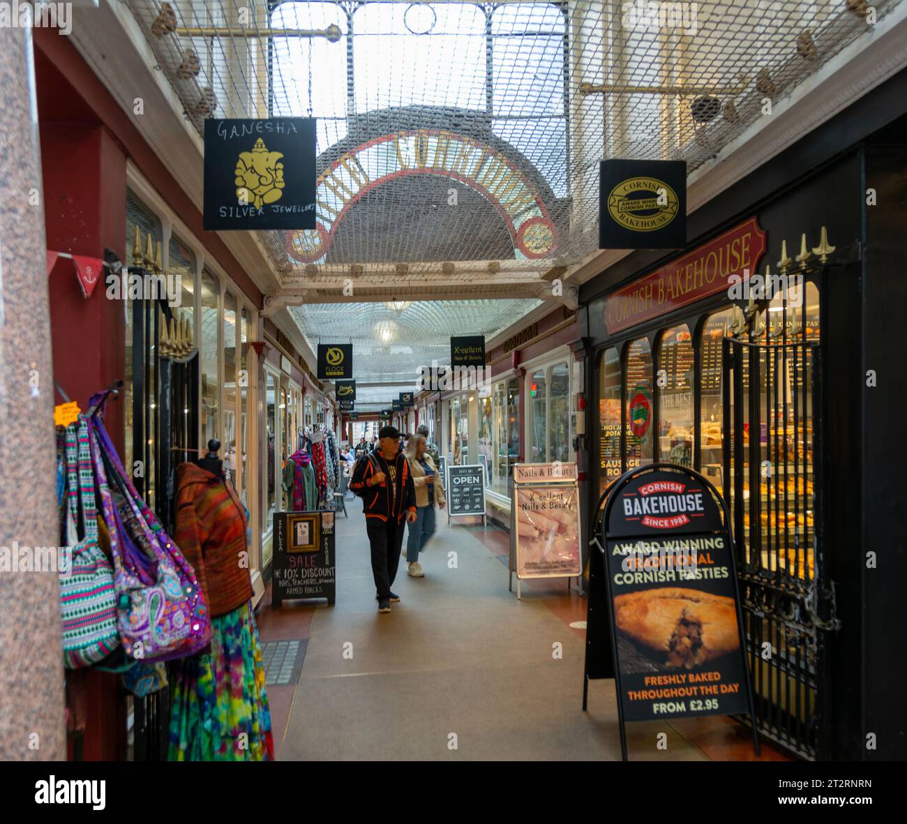 Shoppers walking in pedestrianised covered indoor arcade in city centre ...