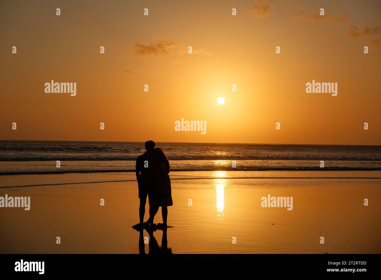 In the intimate shadows, a couple stands hand in hand, their ...