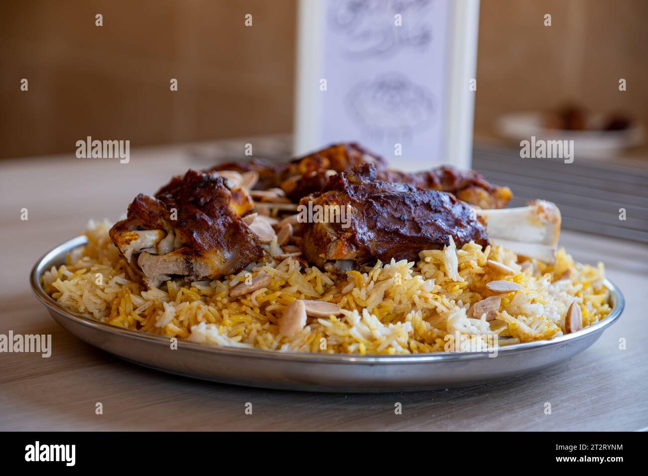 Plate of meat and rice topped with almonds on wooden table for eid adha ...