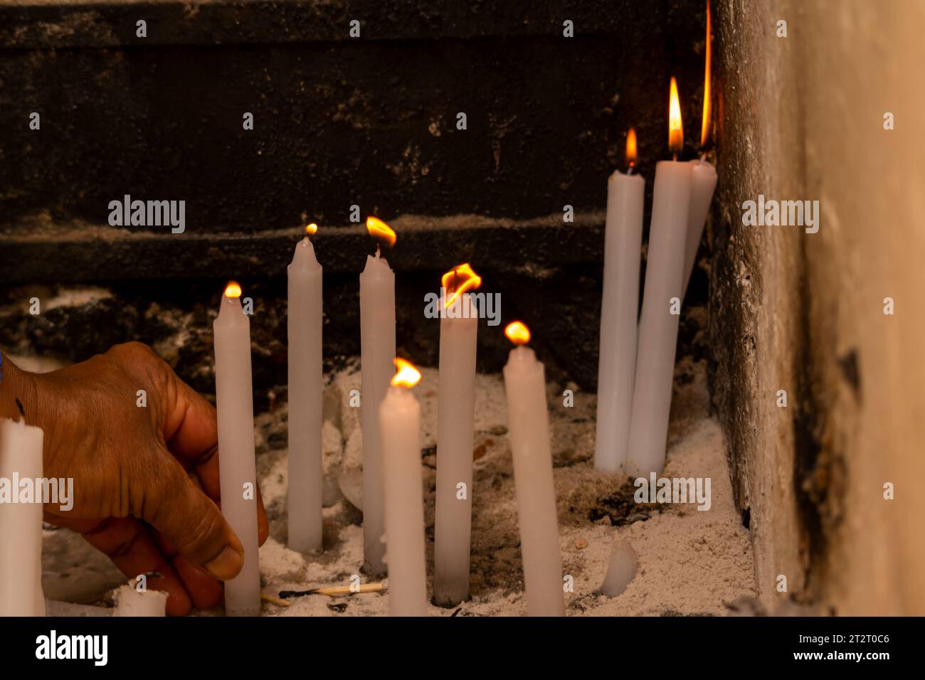 Candles being lit by a human hand. Religious request concept. yellow ...